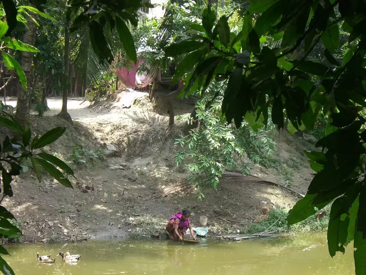 Frau, die Wasser aus einem verschmutzten Fluss bekommt