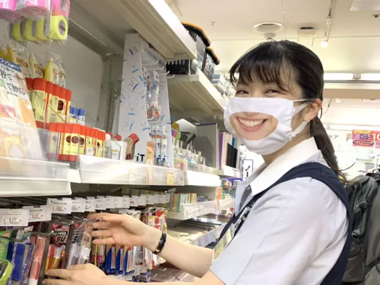 Le personnel de la boutique japonaise porte des masques souriants pour avoir l'air amical