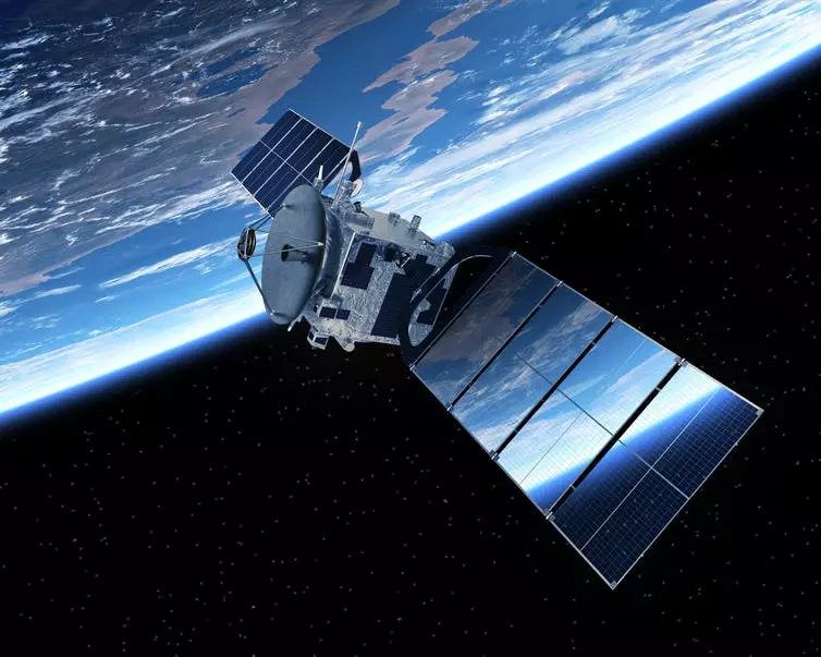 Спутник на космической орбите вокруг Земли (виден на заднем плане)