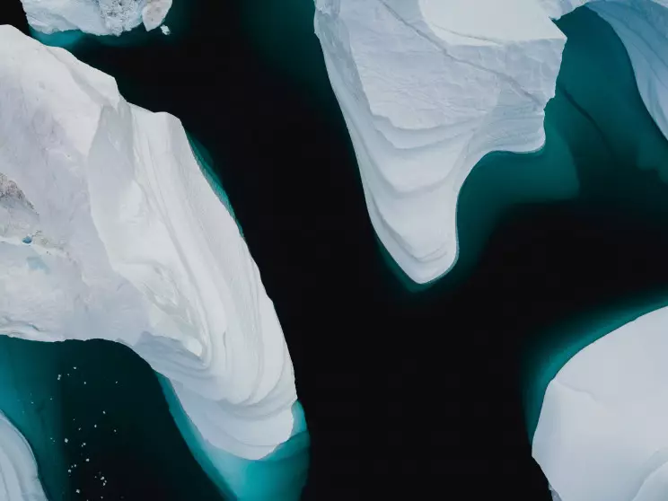 O vedere de sus în jos a trei aisberguri pe jumătate scufundate în apă.
